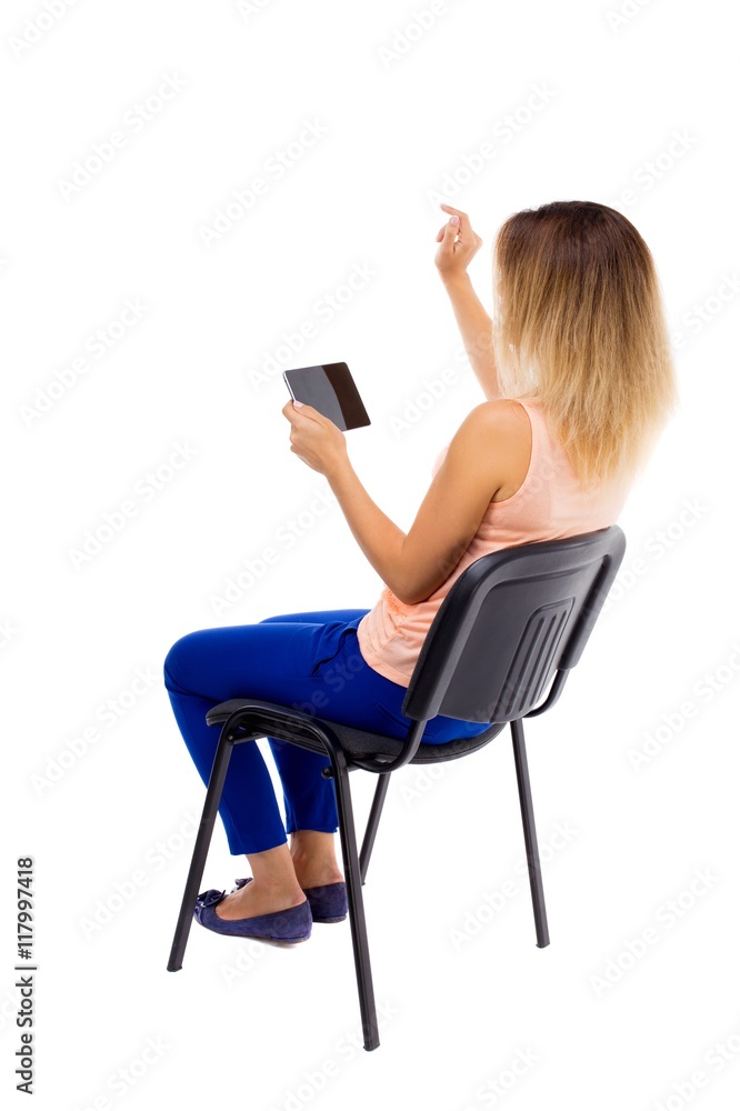 back view of pointing woman sitting on chair and looks at the screen of ...