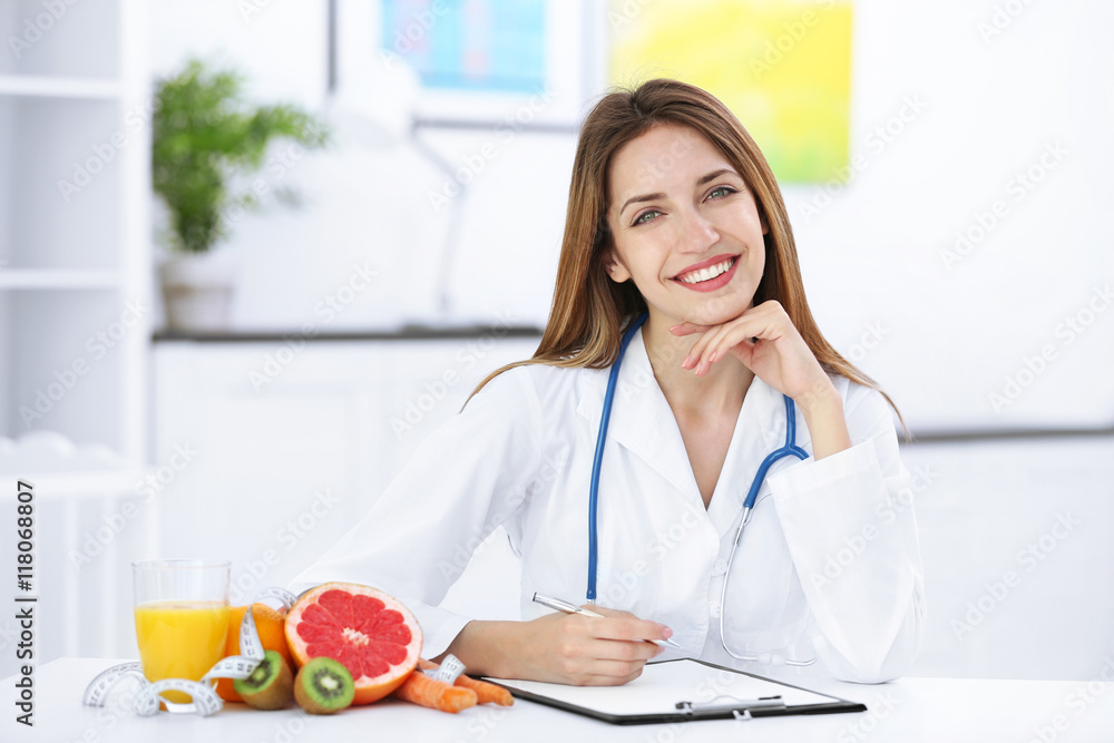 Female nutritionist with fruits working at her desk Stock Photo | Adobe ...