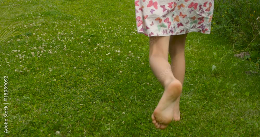 Camera following sweet girl in pink dress running away in the garden ...