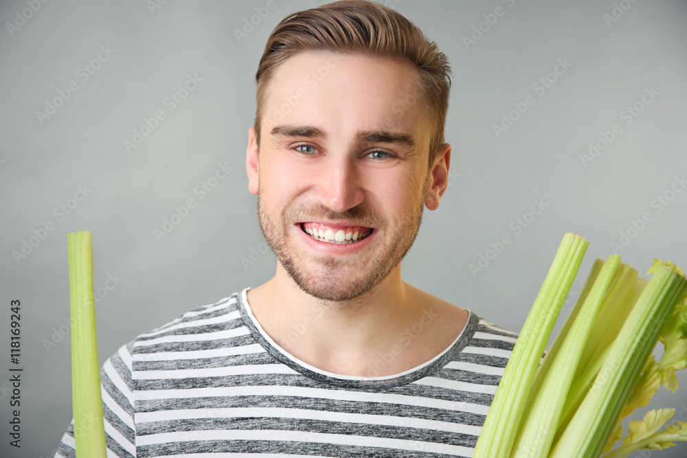 Handsome man eating celery on grey background Stock Photo | Adobe Stock