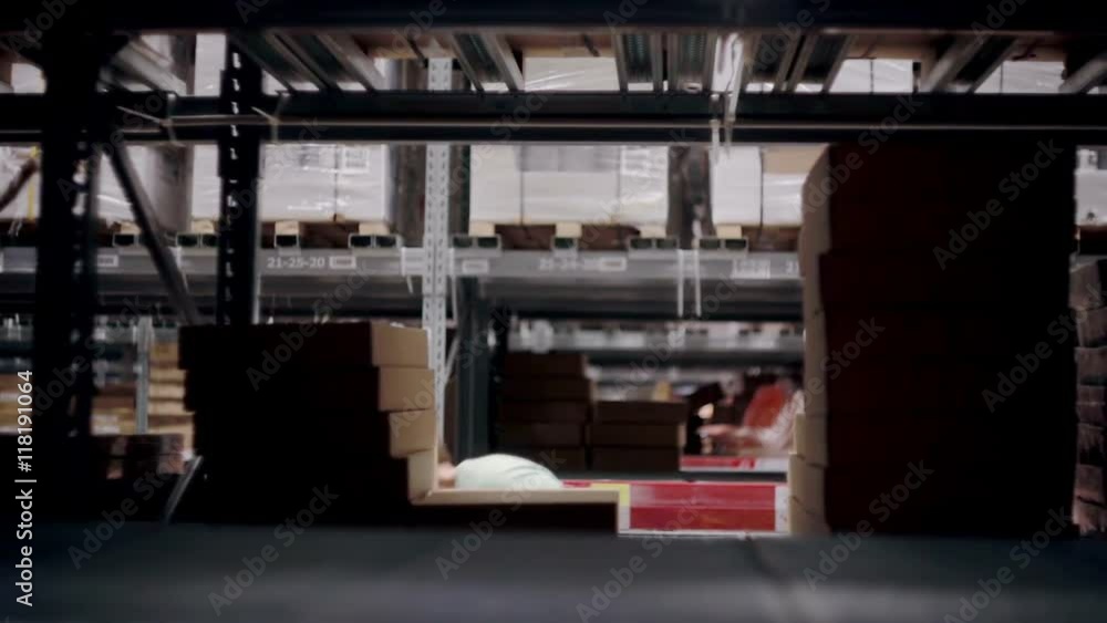 A man is taking boxes from the shelves, putting them on the trolley in ...