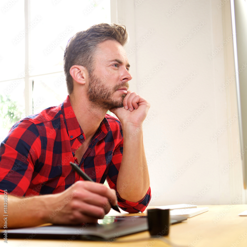 Man thinking sitting at desk with stylus Stock Photo | Adobe Stock