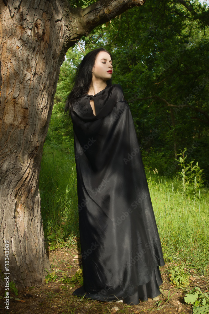 Beautiful brunette woman in black dress and black cloak in the m Stock ...