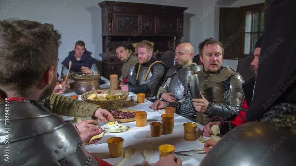 Knights are sitting behind a table and one of the knights is still ...