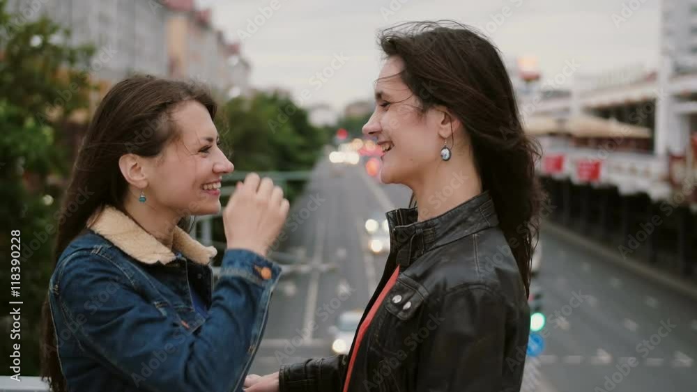 Two beautiful girls best friends met at the city bridge, hugging ...