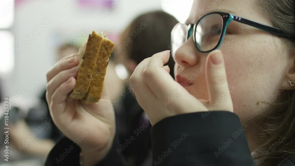 Close up portrait of girl eating a sandwich in school cafeteria Stock ...
