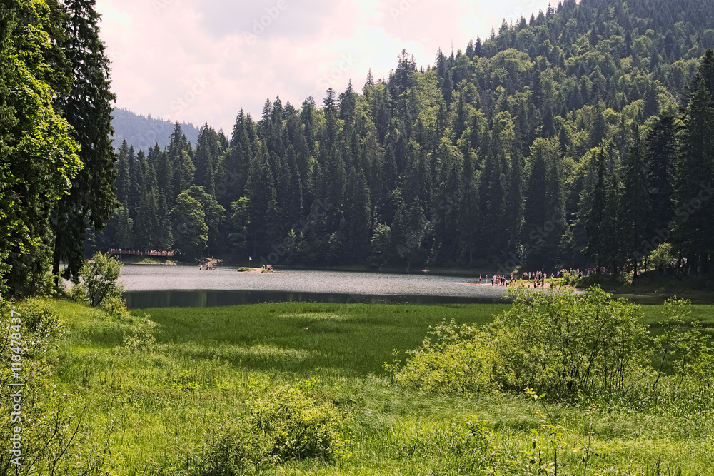 Morning in Lake Sinevir. Tourists are contemplateing the lake and its ...