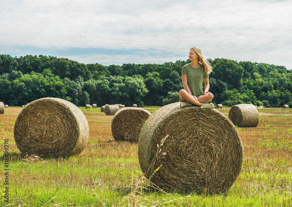Young Blond Girl With Long Hair Sitting Legs Crossed On Haystack And