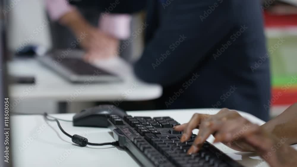 Teacher showing student how to use computer in adult education class ...