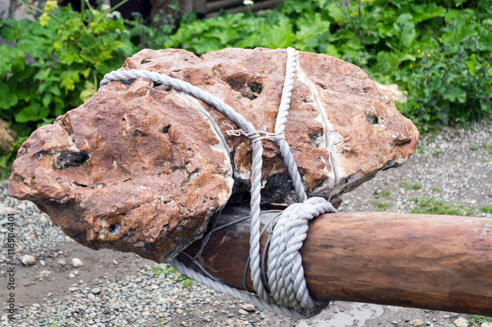 A large stone tied a thick rope to a log. Stock Photo | Adobe Stock