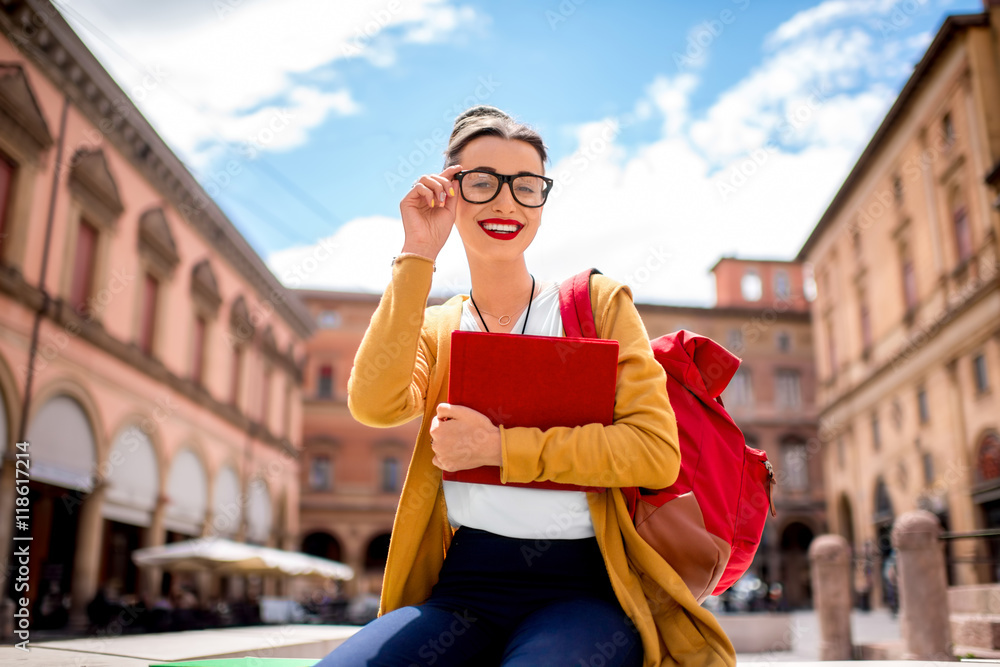 Young female student dressed casually sitting with book on the central ...