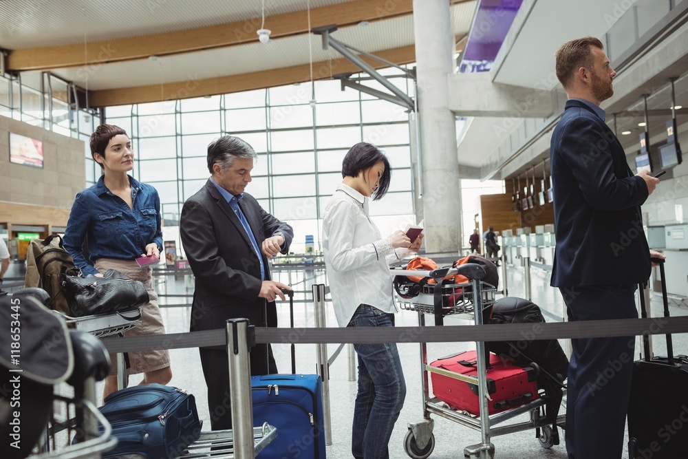 Passengers waiting in queue at a check-in counter with luggage Stock ...