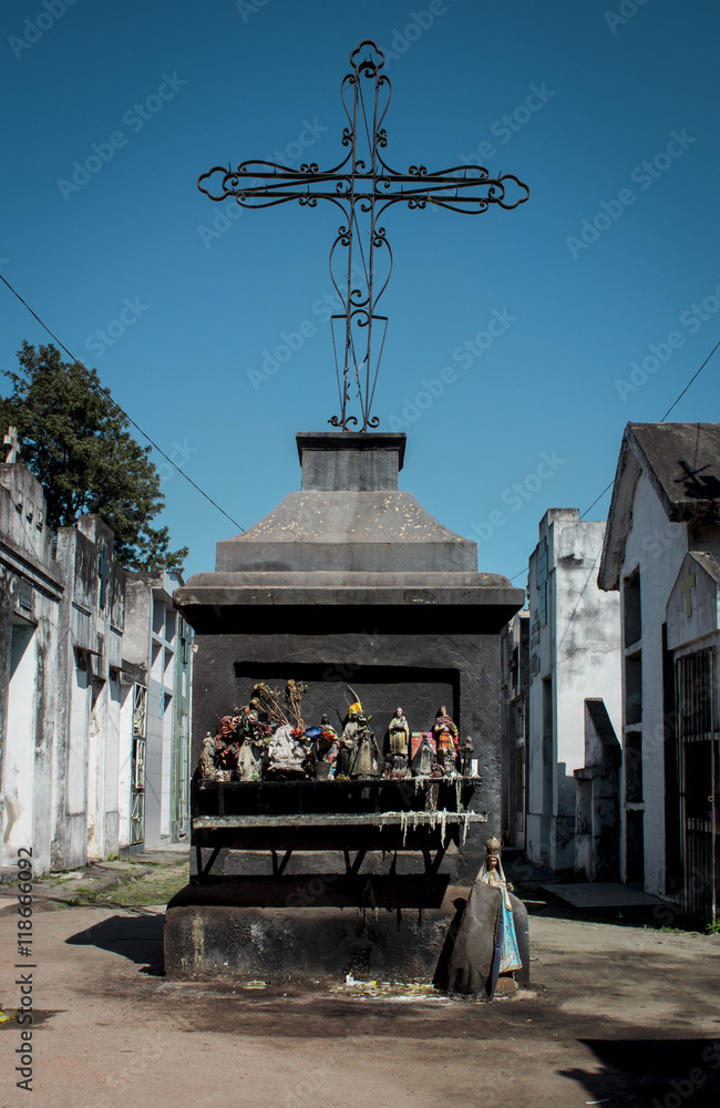 Foto de cruz mayor en cementerio con estatuas pequeñas de santos y ...