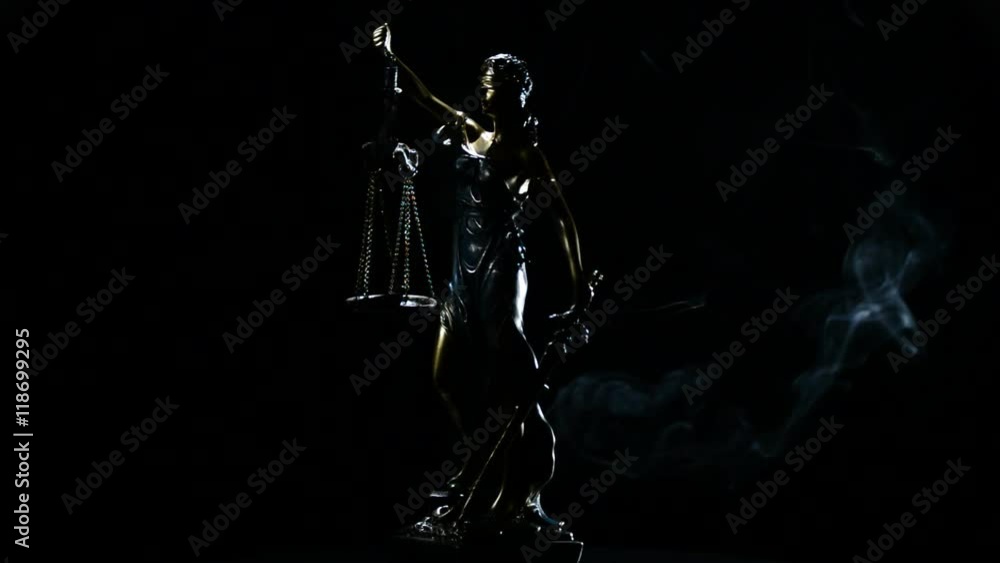 Lady justice in rotation over black background with strands of smoke ...