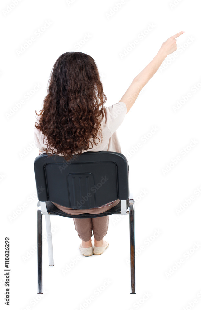 back view of young beautiful woman sitting on chair and pointing. girl ...