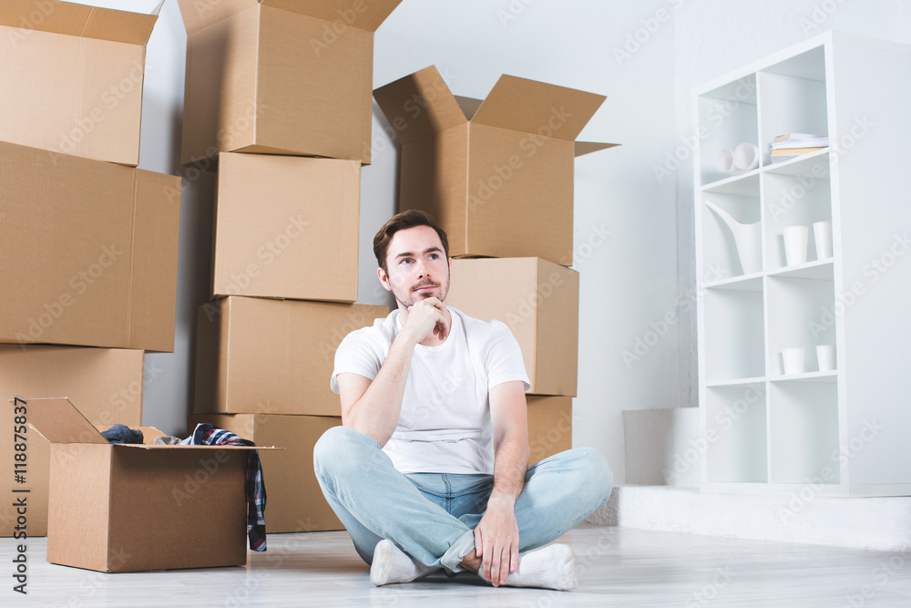 Young man thought sitting on the floor. Moving in house. Stock Photo ...