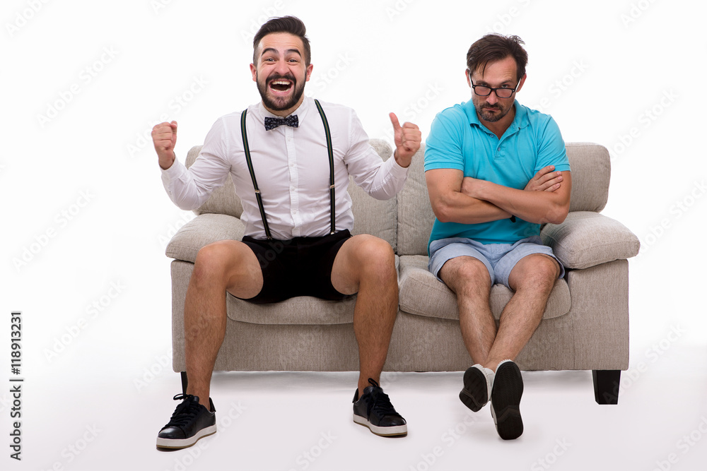Picture of two excited men sitting on couch or sofa and looking at ...