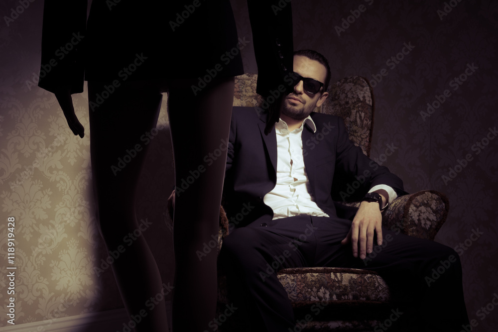 Young and elegant man sitting in chair looking at woman standing in ...