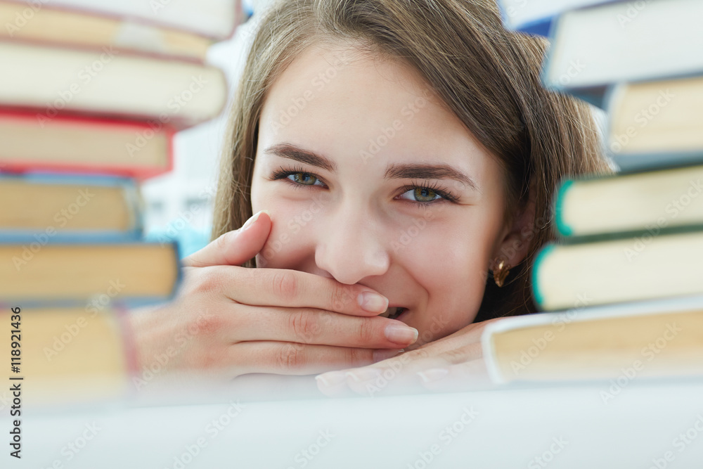 Young girl hiding in a pile of books in the library. Stock 写真 | Adobe Stock