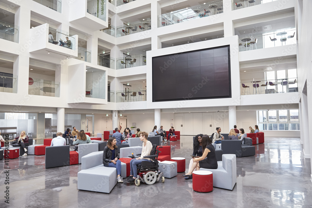 Students socialising under AV screen in atrium at university Stock ...