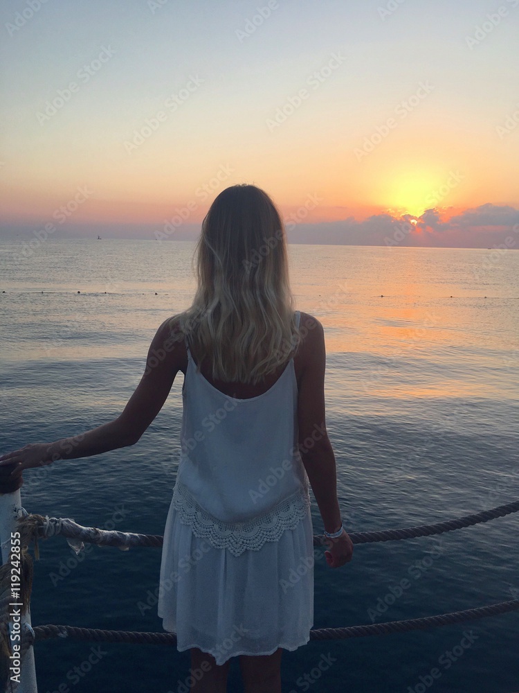 Beautiful girl meets sunrise at sea Stock Photo | Adobe Stock