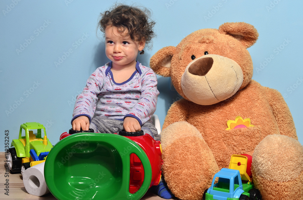 Baby toddler sitting on a potty surrounded by teddy bears. Cute kid ...