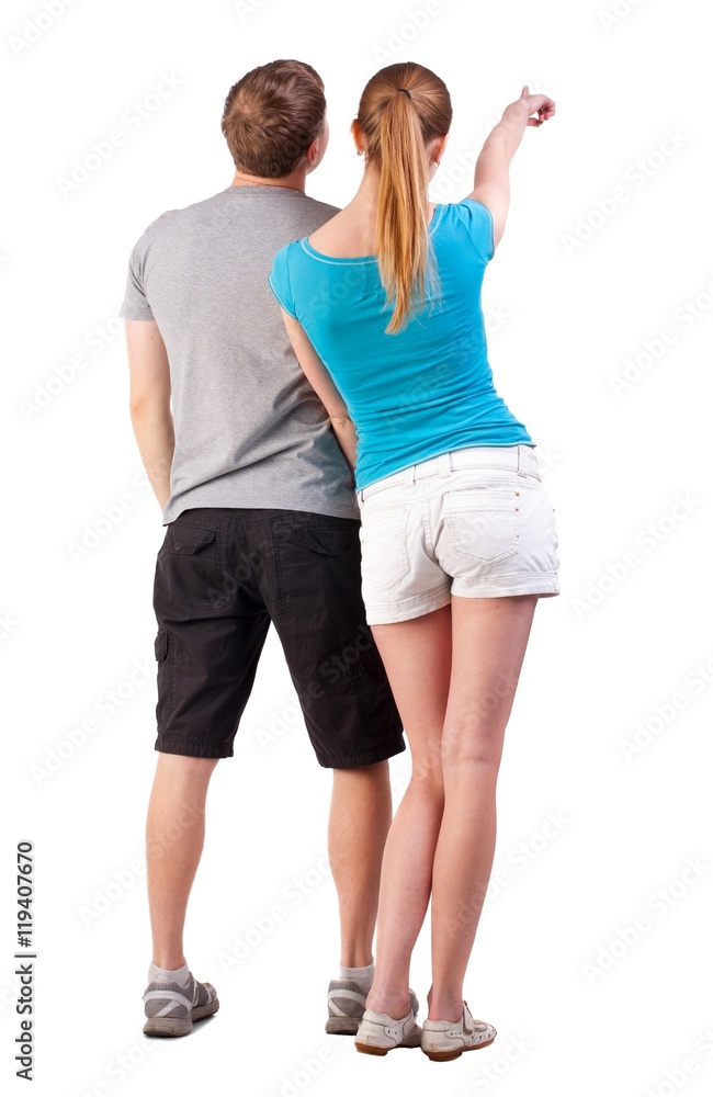 Back view of young couple pointing at wall (woman and man). Rear view ...