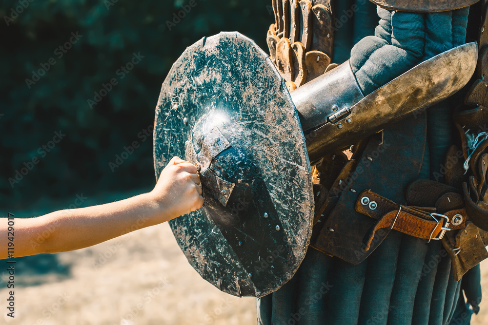 Little boy rests his fist on the knight bruised cracked worn shield ...