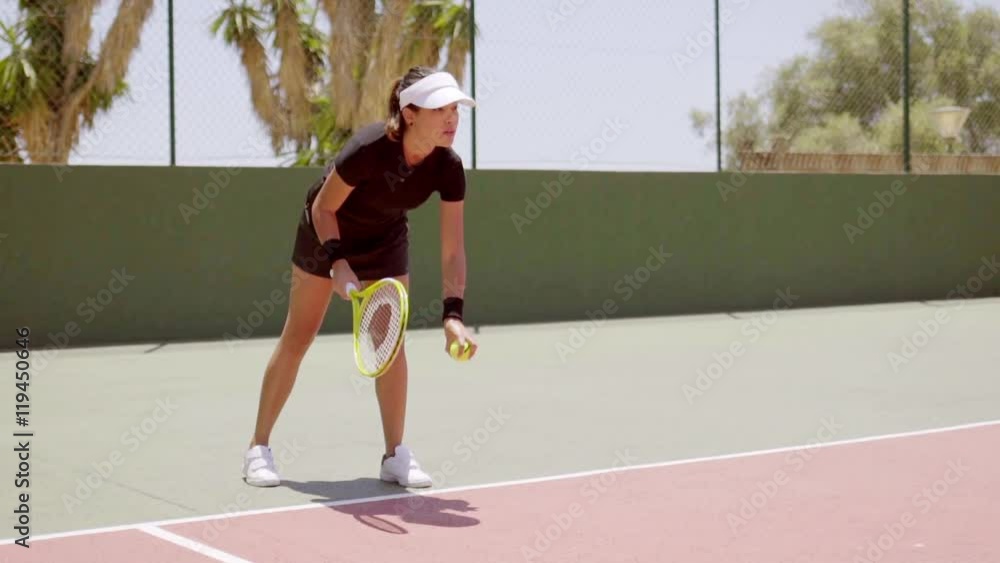 Athletic woman tennis player serving the ball tossing it in the air as ...