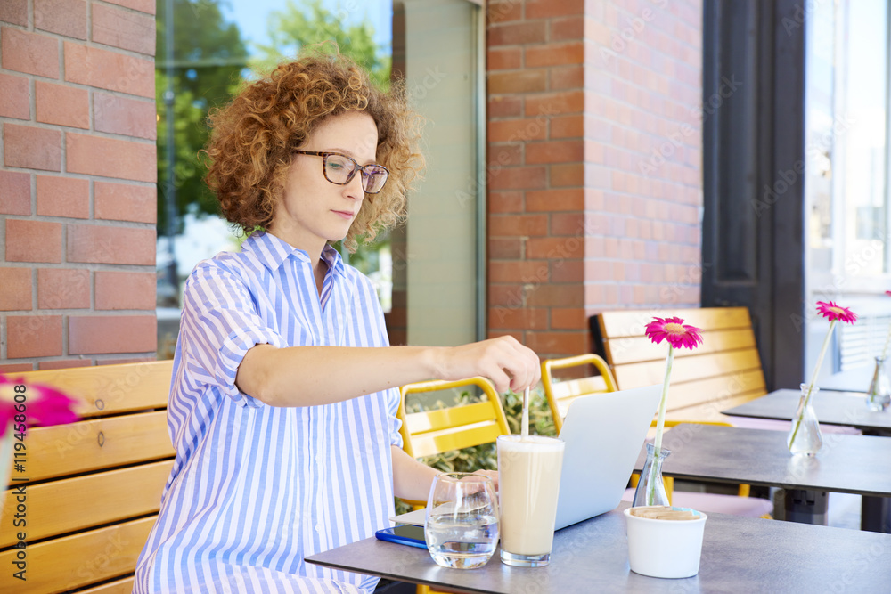 Morning in the coffee shop. Shot of a young female assistant sitting at ...
