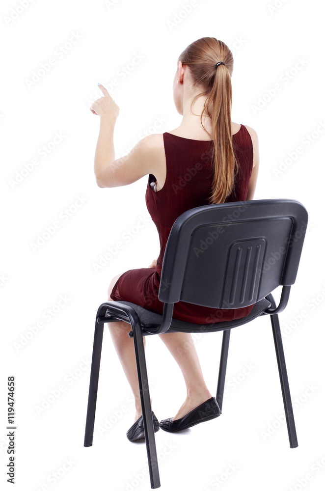 back view of young beautiful woman sitting on chair and pointing. girl ...