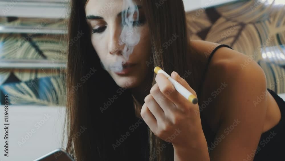 Portrait of young girl sit on toilet with phone and smoke electronic ...