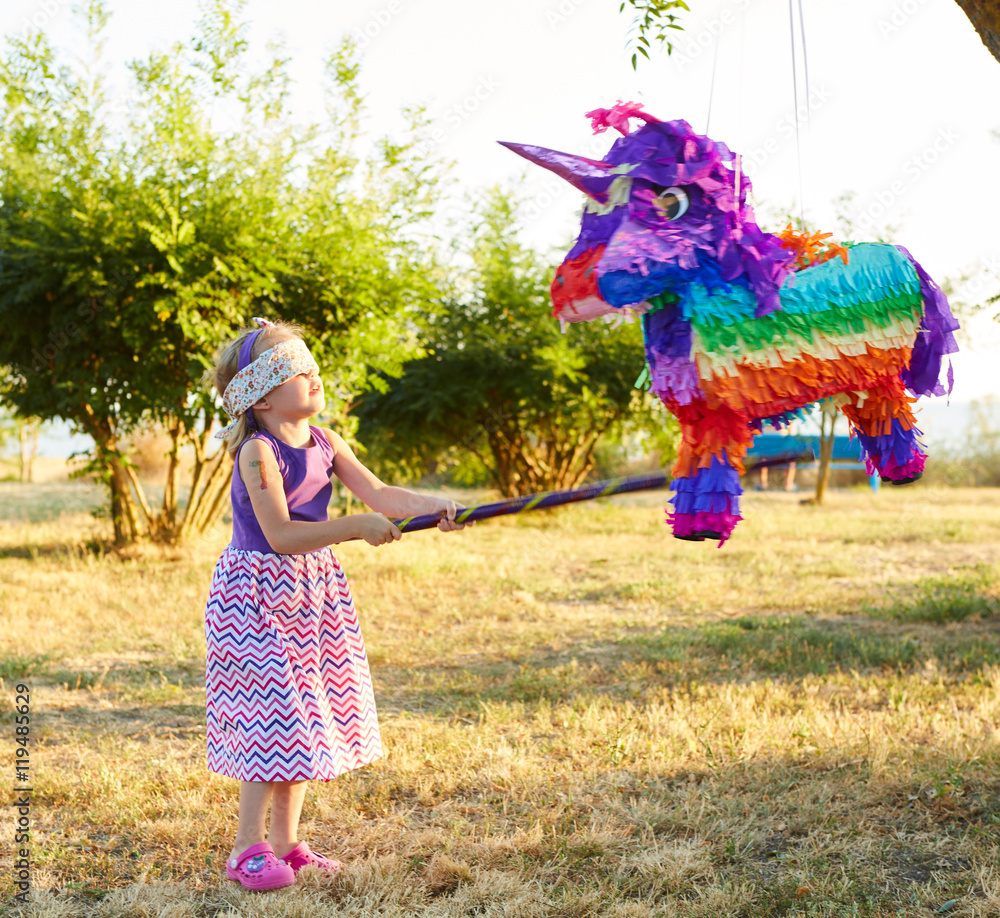 Young girl at an outdoor party hitting a pinata Stock Photo | Adobe Stock