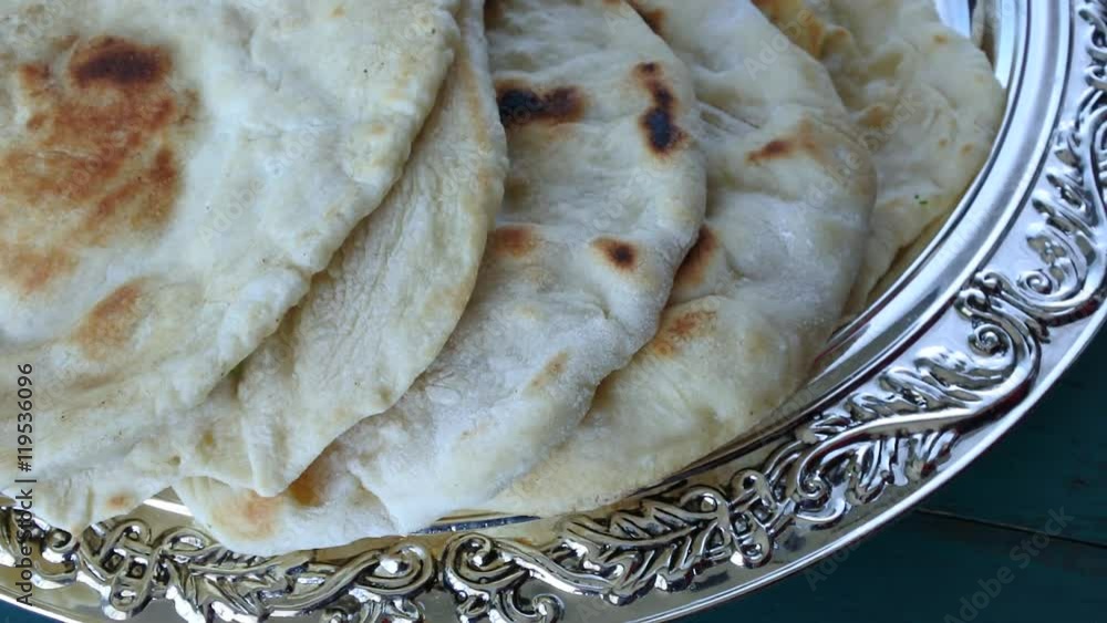 Indian woman hands serve Naan, nan or khamiri leavened, oven-baked ...