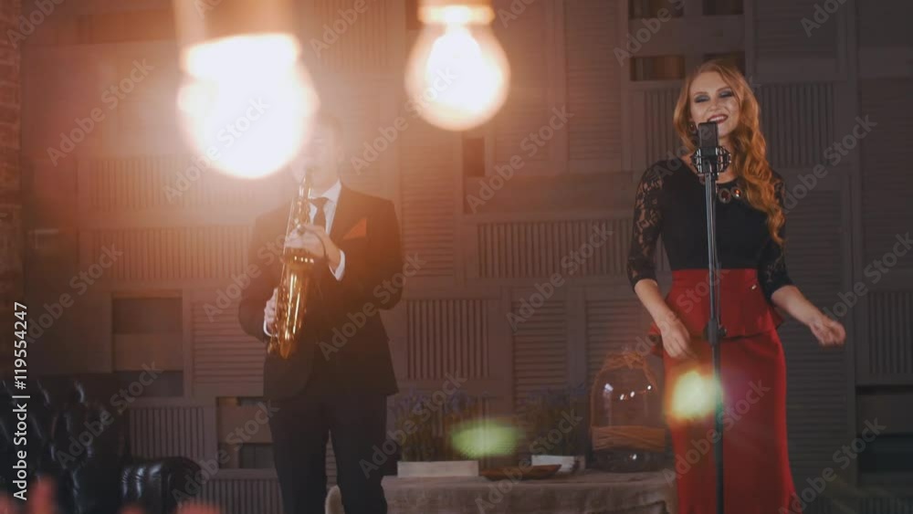 Jazz duet perform on stage. Saxophonist in suit. Vocalist click fingers ...