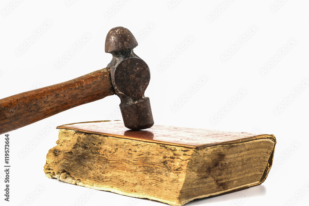 A hammer on an old book with a white background. Stock Photo | Adobe Stock