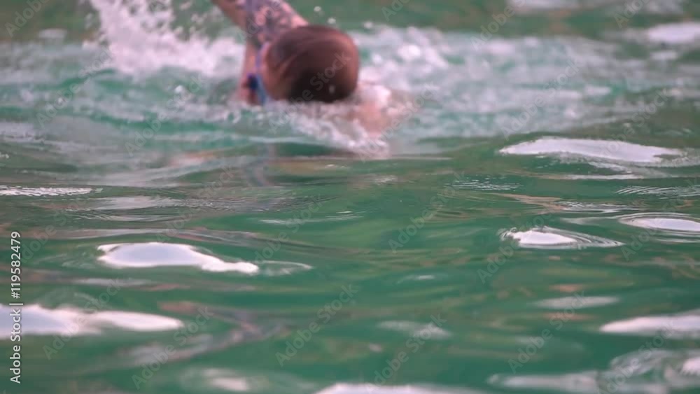 Fit swimmer doing the butterfly stroke in the swimming pool in slow ...