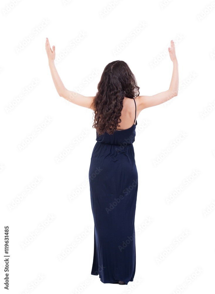 Back view of Beautiful woman in dress looking at wall and Holds hand up ...