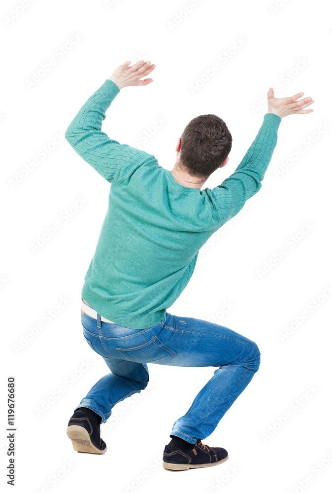 back view. man protects hands from what is falling from above. Man ...