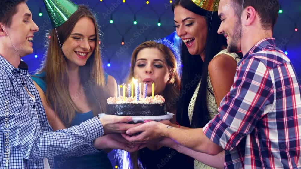 Girl With Friends Men Celebrate Birthday And Blow Out Candles On Cake