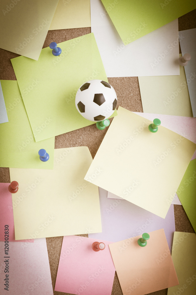 Football or soccer ball and blank sticky notes on notice board in ...