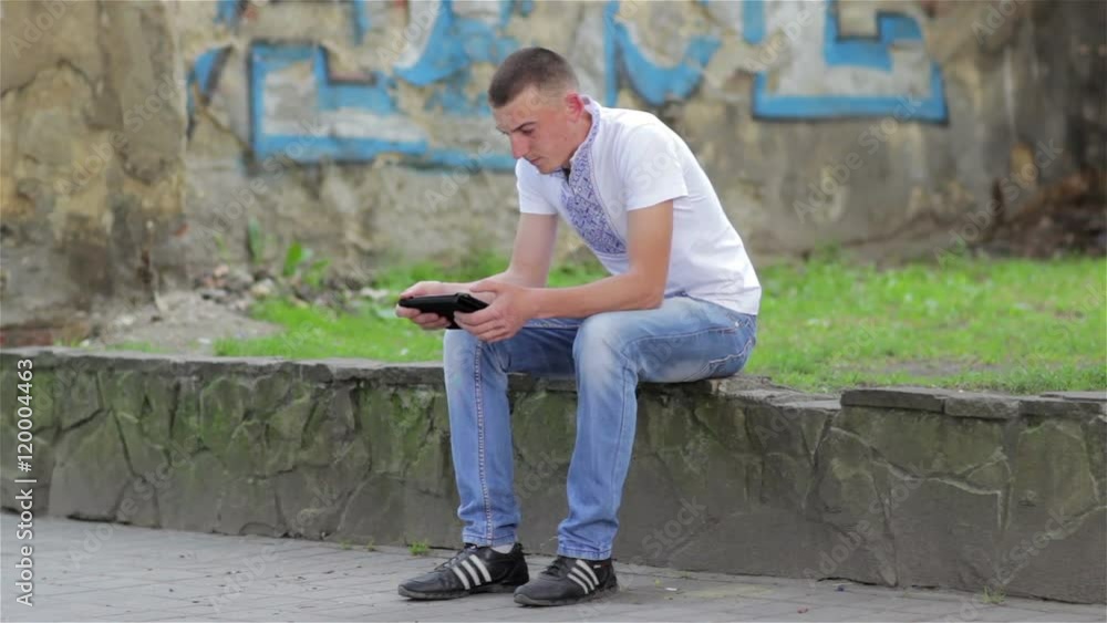 Vidéo Stock boy with the tablet on stone/boy sits on a stone on a ...