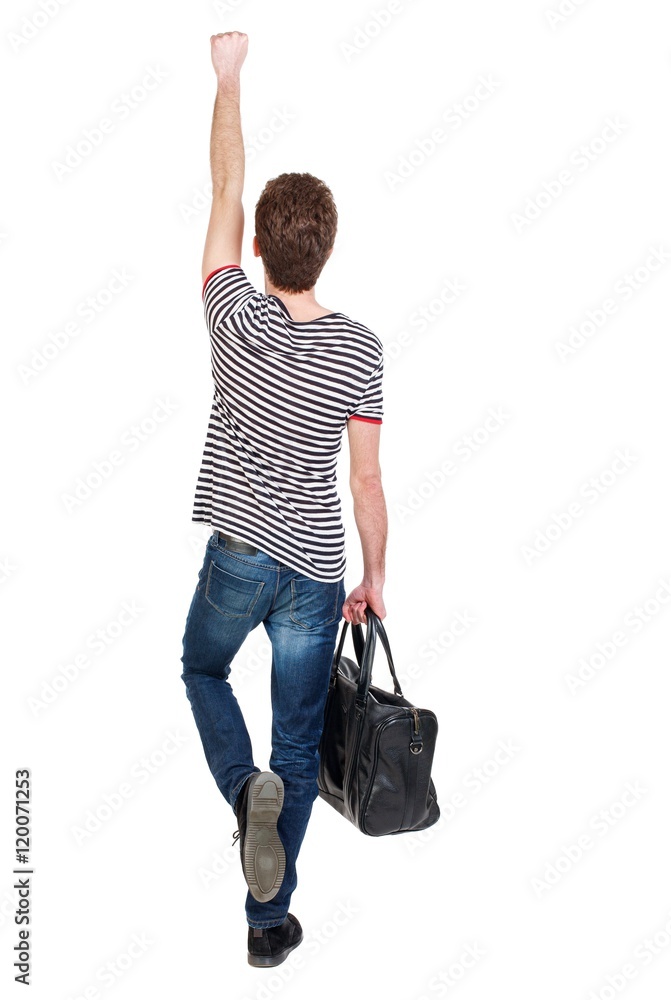 Back view of man with bag. Curly boy in a striped vest holding a bag in ...