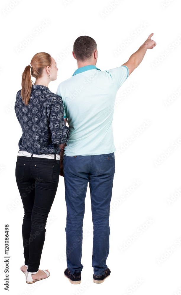 young couple pointing at wal Back view woman and man . Rear view people ...