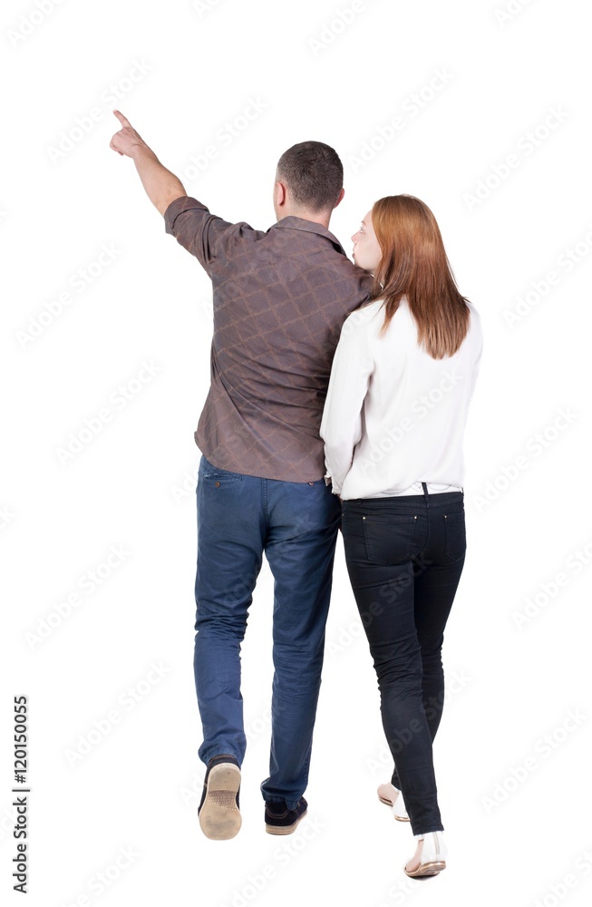 Back view of walking young couple (man and woman) pointing. Rear view ...