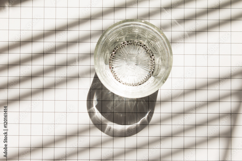 Top view of a glass of water on grid background. Light and shadow from ...
