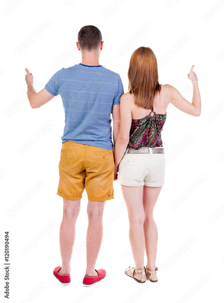 young couple pointing at wal Back view woman and man . Rear view people ...