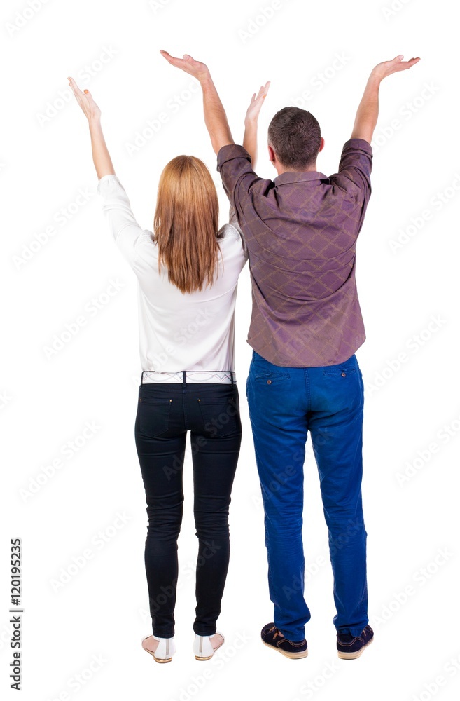 Back view couple looking at wall and Holds hand up. Rear view people ...