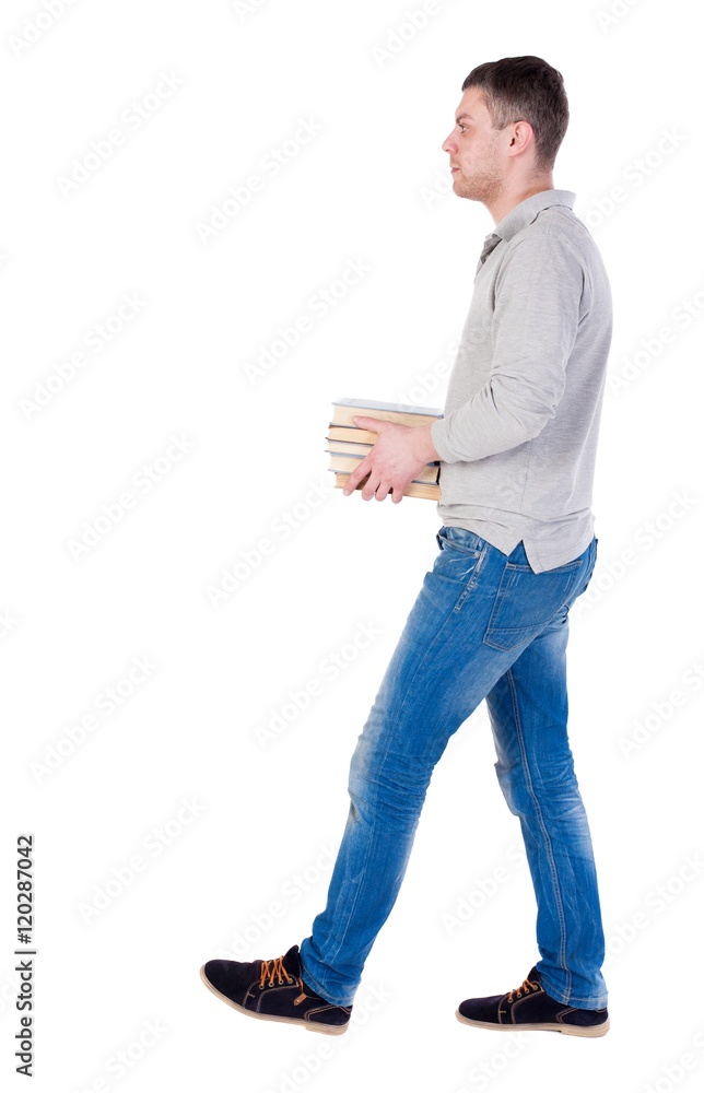 Back view of going handsome man carries a stack of books. walking young ...