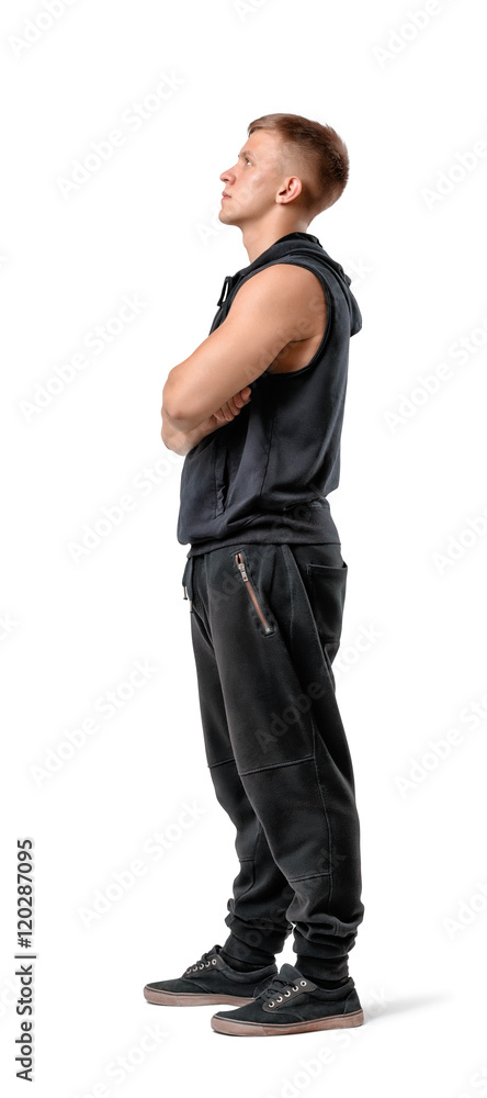 Side view of muscled young man standing with his arms folded looking up ...